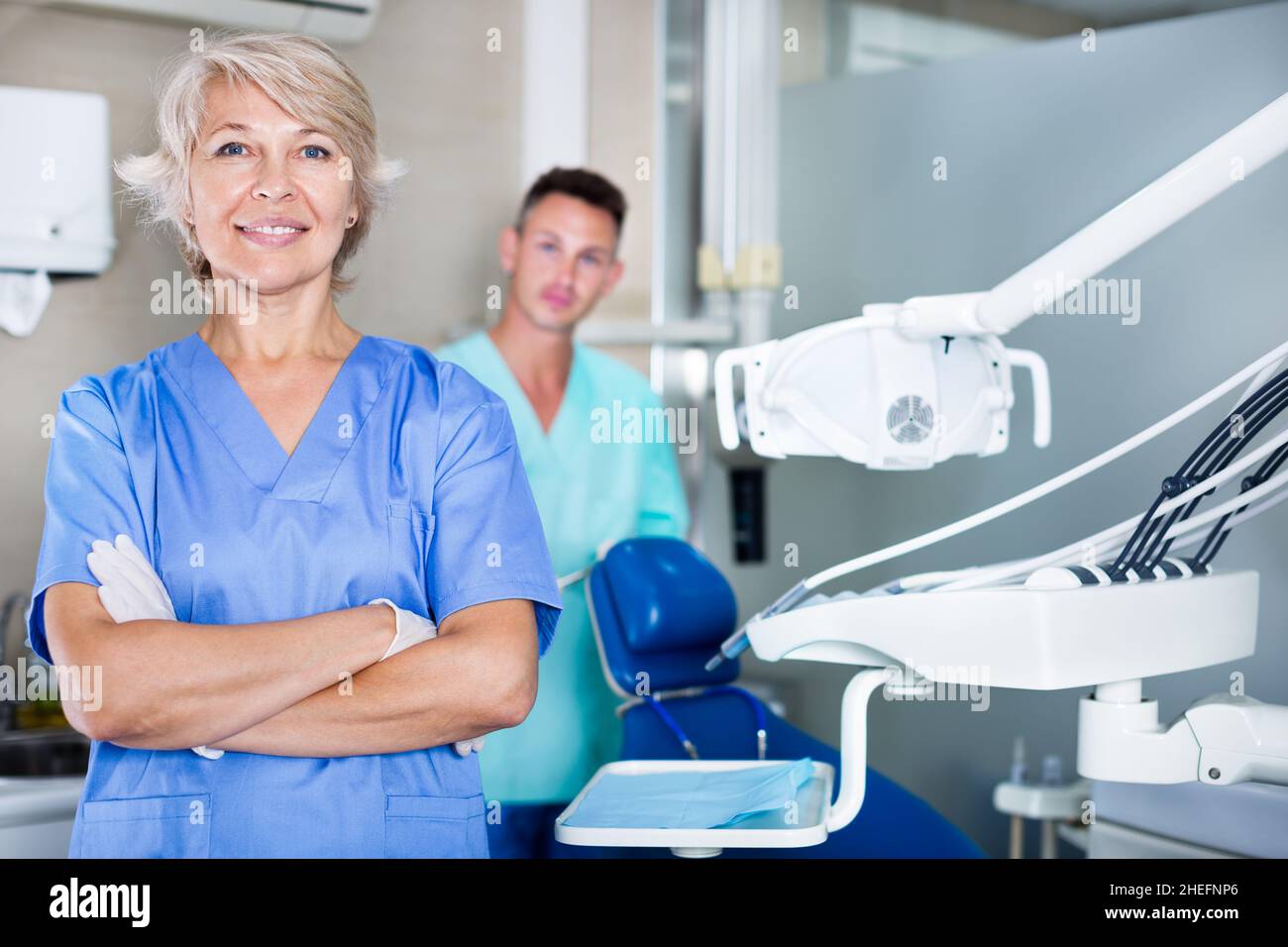 Dentist standing in dental office with hands crossed Stock Photo - Alamy