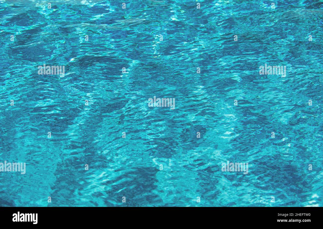 Background of blue water in swimming pool with sun reflection, ripple water wave in pool. Clear ...