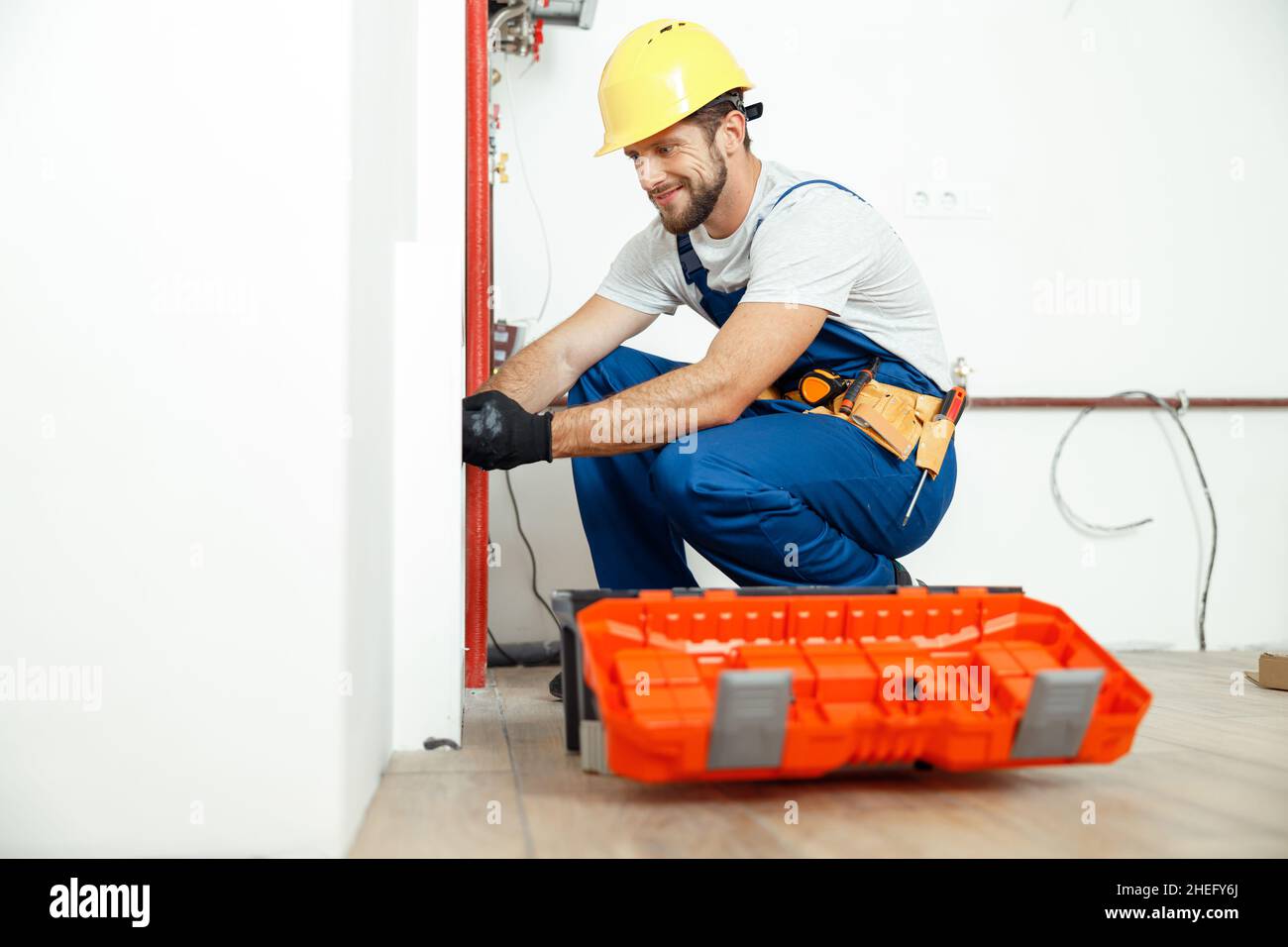 Hardworking technician, plumber in uniform using tools from toolbox ...