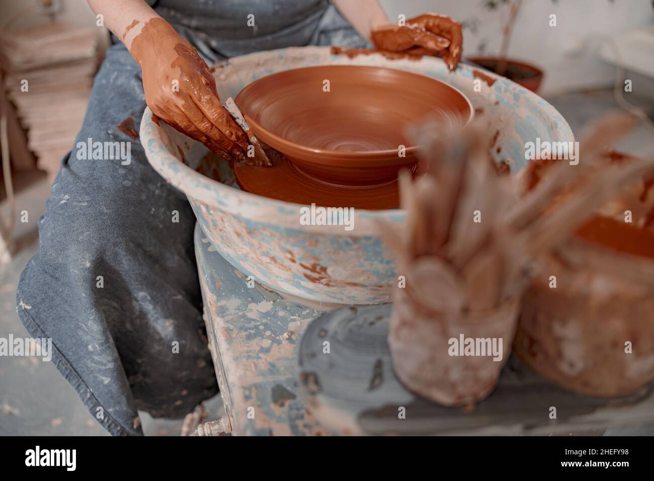 Skillful female potter creating earthen bowl on circle in workroom ...