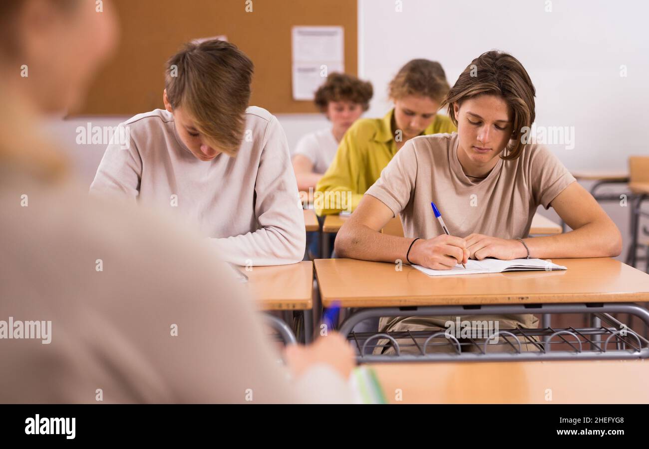 School lesson - students write down assignments while sitting at desks ...