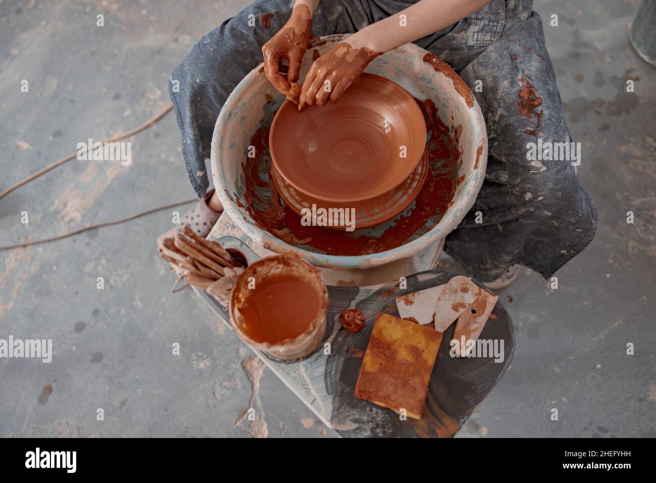 Handmade artist creating earthen bowl on circle in pottery workshop ...