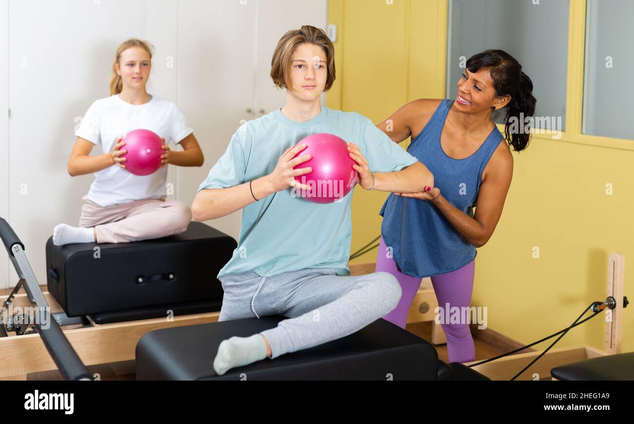 Pilates instructor shows boy how to exercise with ball Stock Photo - Alamy