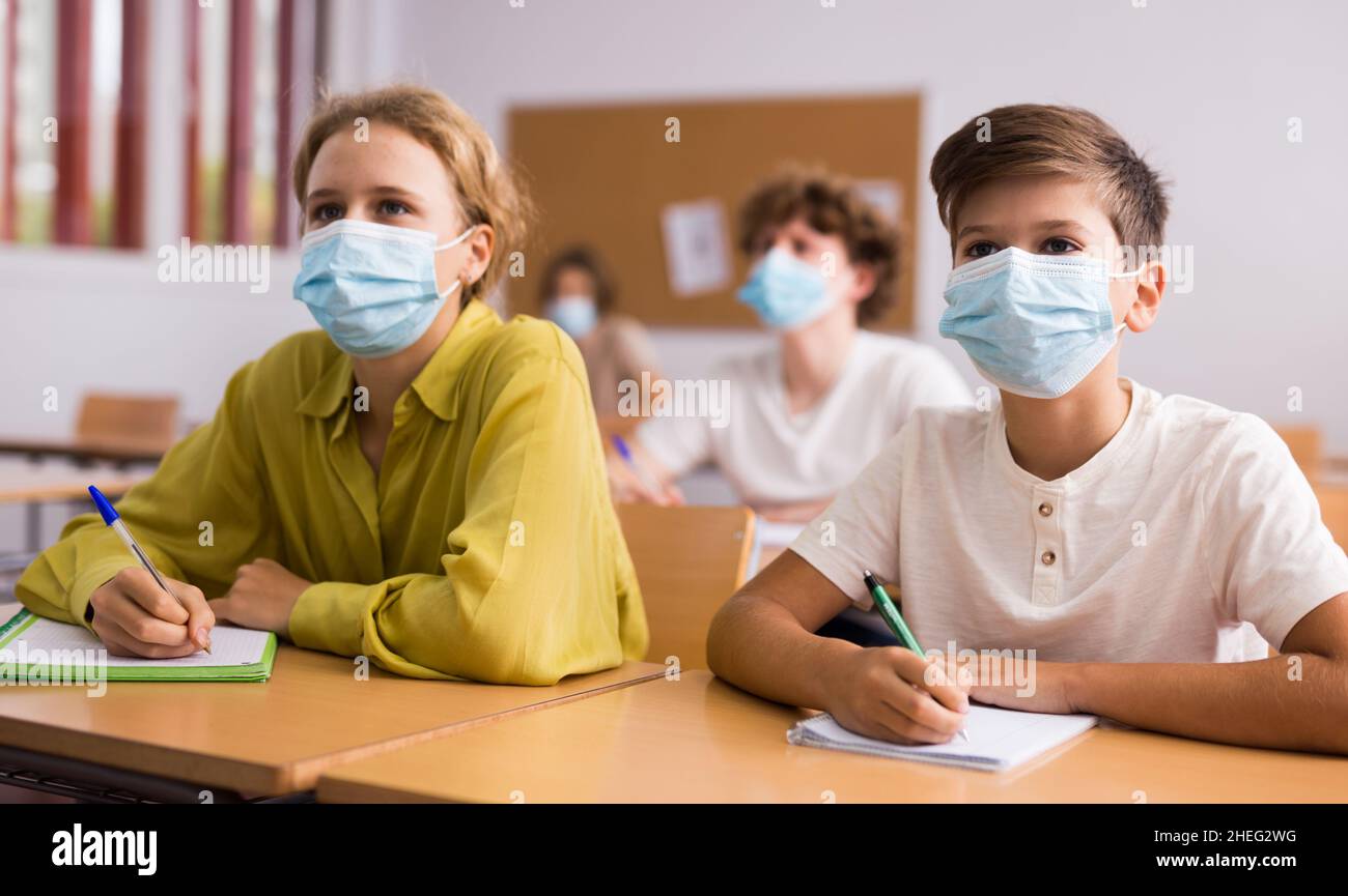 Teenage and young pupils in masks doing tasks during lesson Stock Photo ...