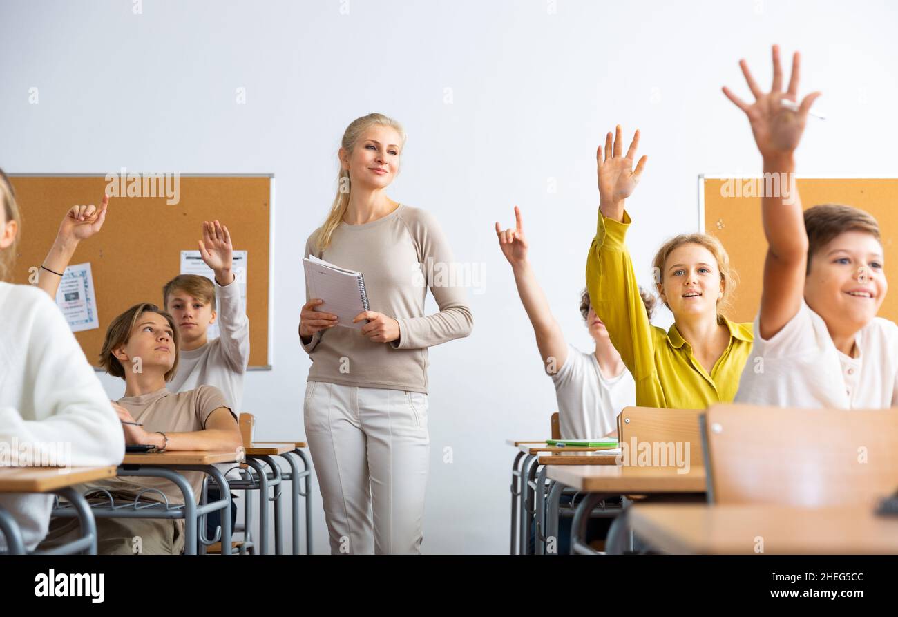 Pupils raising hands during lesson in school Stock Photo - Alamy