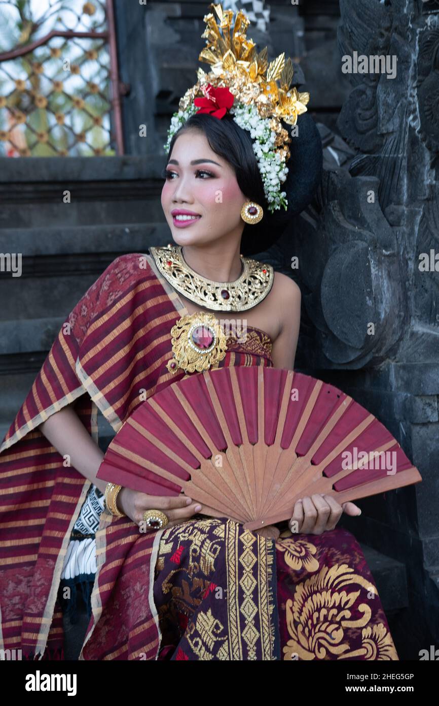 Portrait Bali girl with a traditional dress standing with folding fan ...