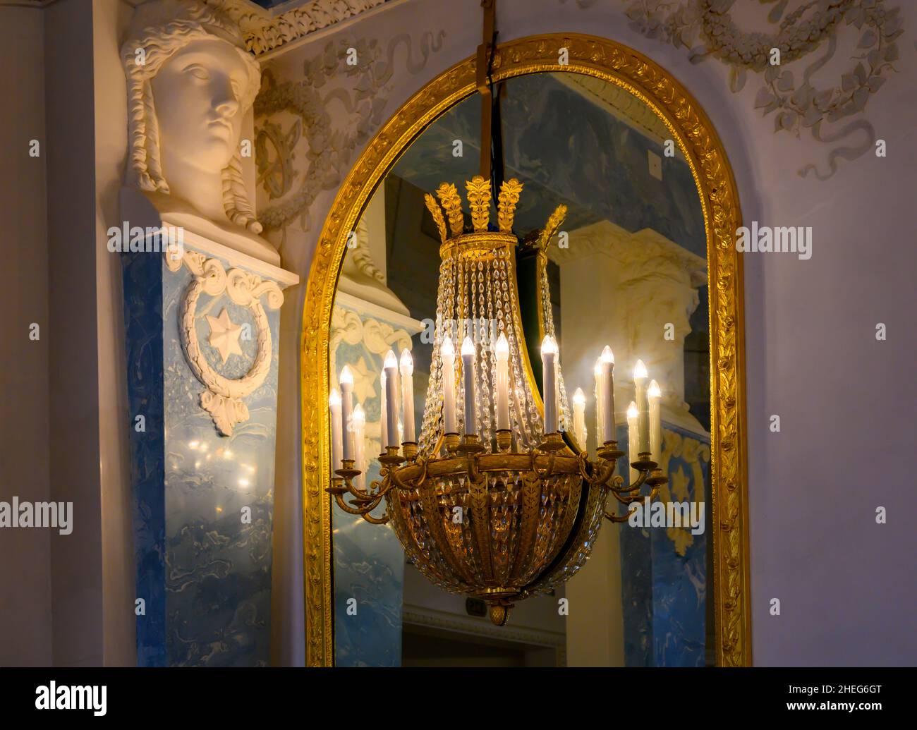 Antique mirror and a chandelier in a dim room decorated with bas ...