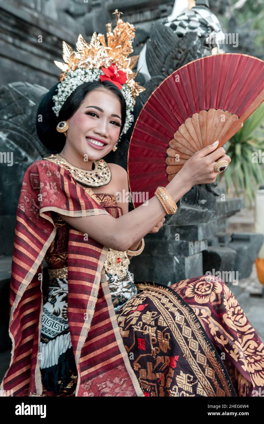 Portrait Bali girl with a traditional dress standing with folding fan ...