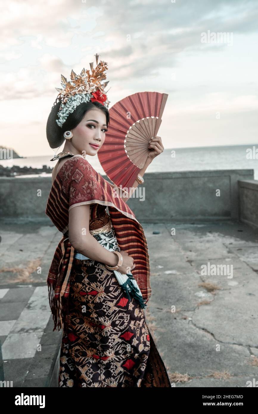 Young local Balinese girl with a traditional dress standing with ...
