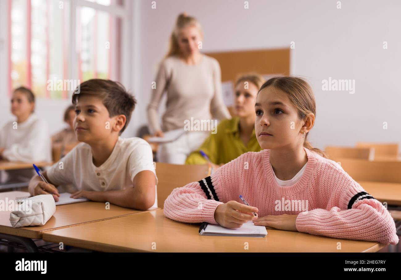 School lesson - students write down assignments while sitting at desks ...
