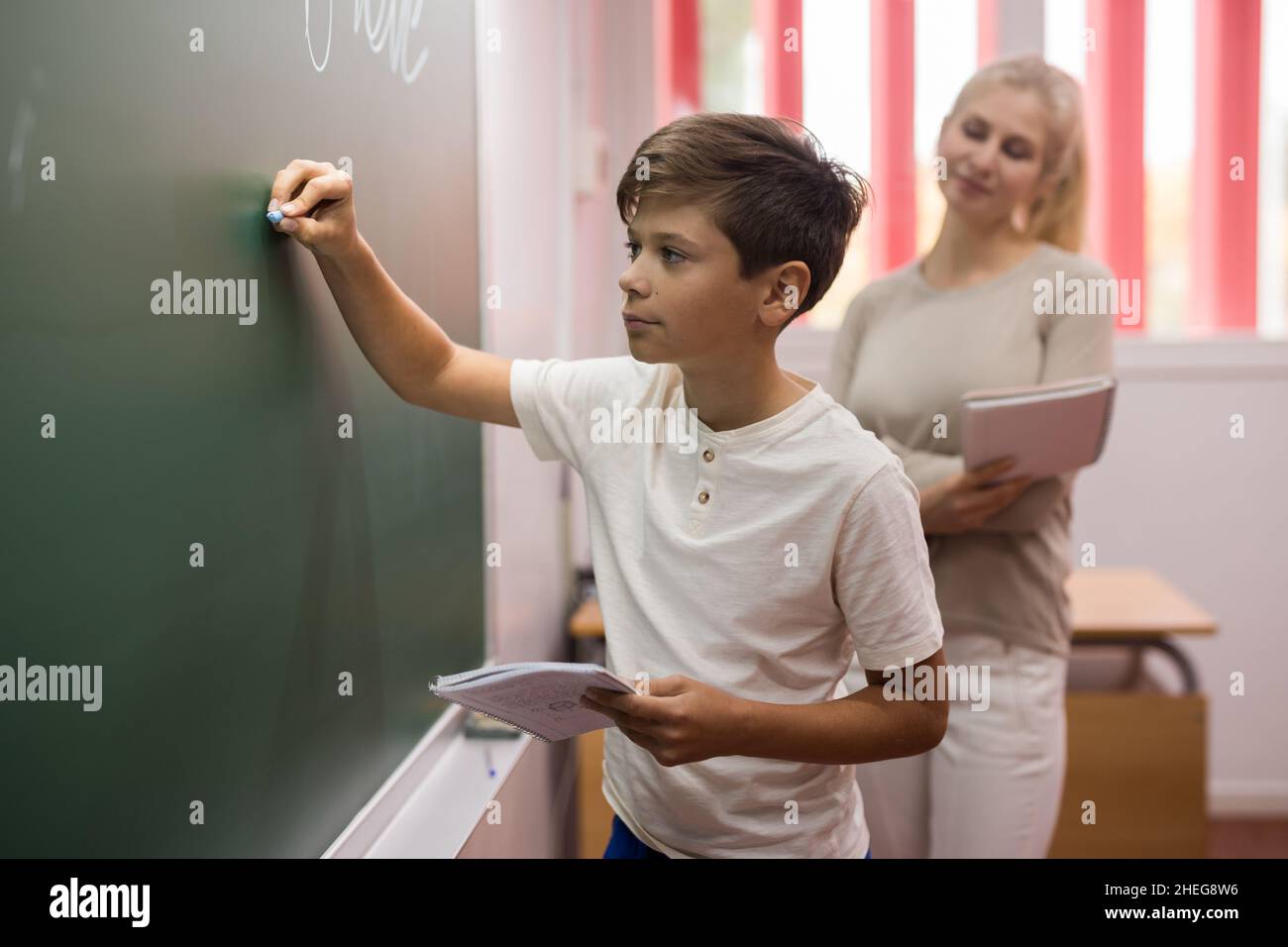 Young boy writing on chalkboard Stock Photo - Alamy