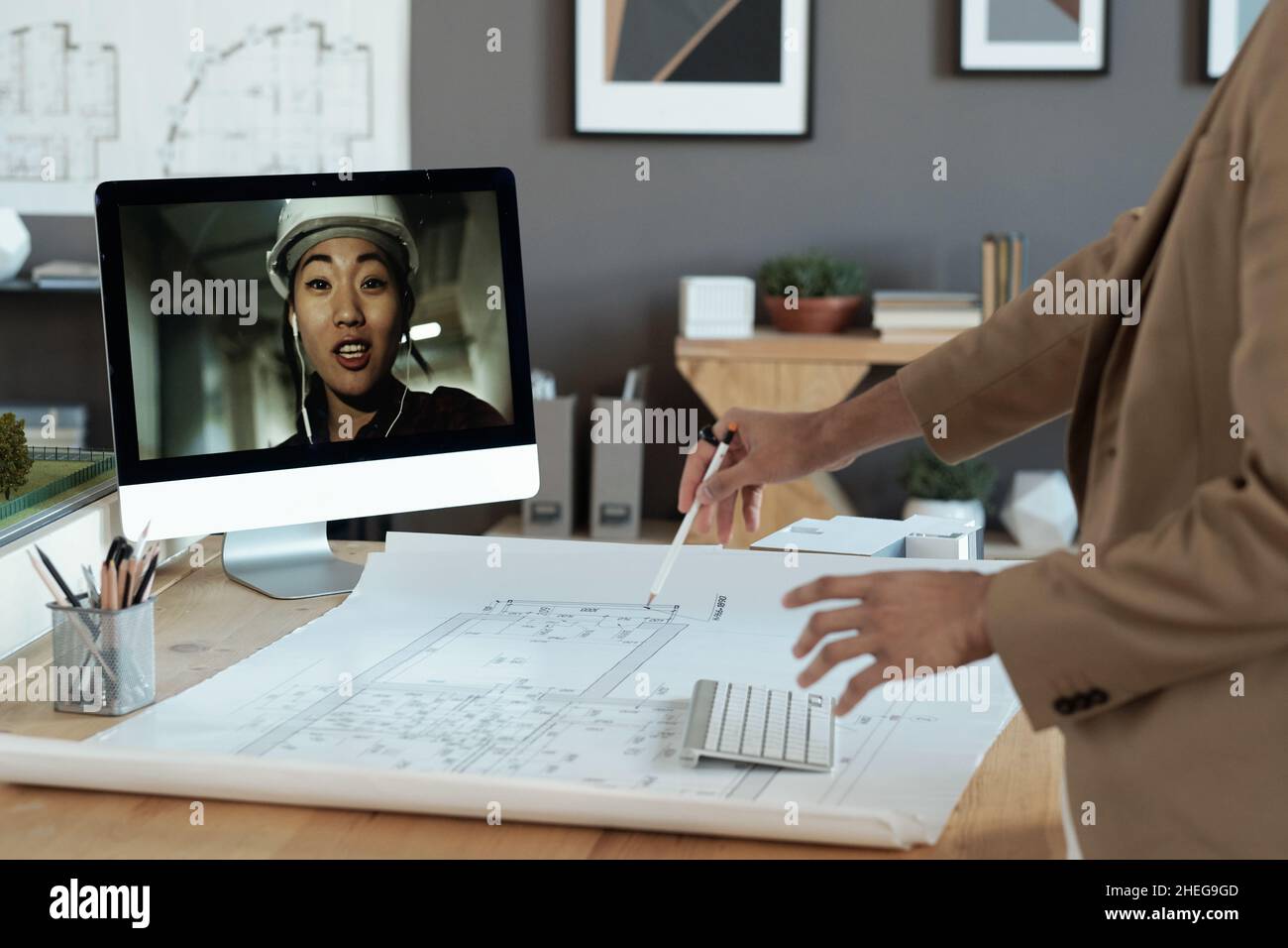 Young Asian female builder in helmet on computer screen talking to male ...