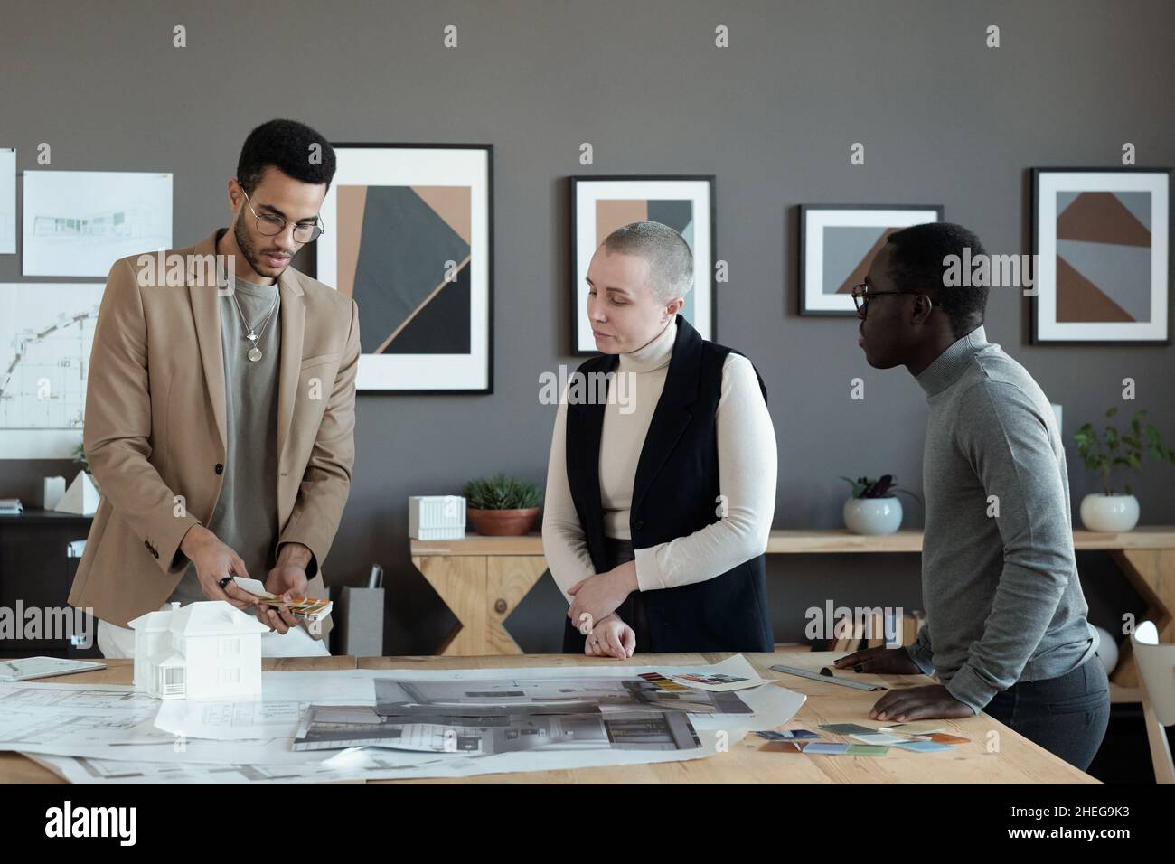 Group of intercultural colleagues choosing color from palette while one ...