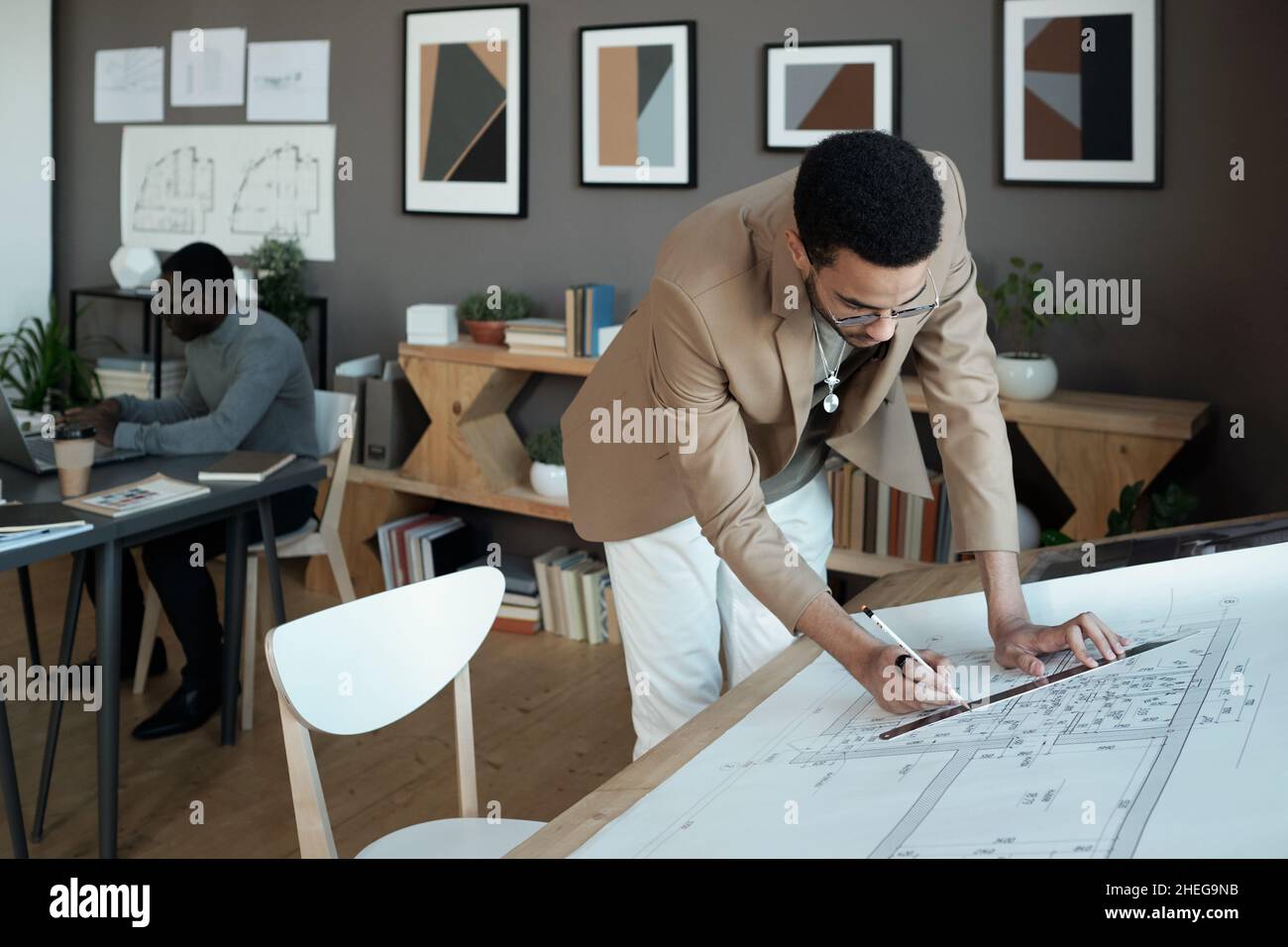 Young biracial architect in smart casualawear drawing line on sketch ...