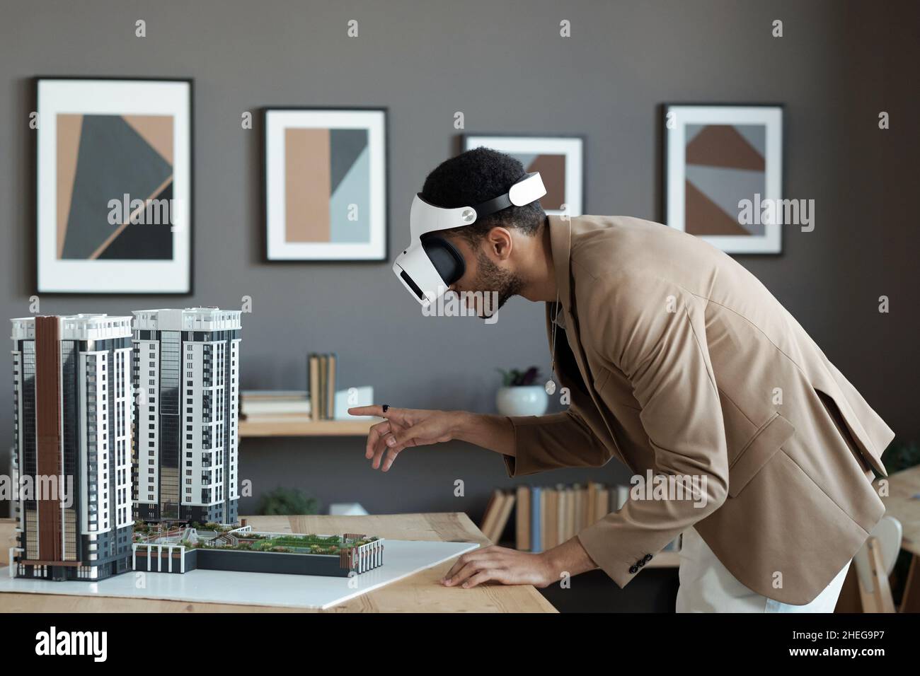 Young biracial businessman in vr headset bending over table and ...