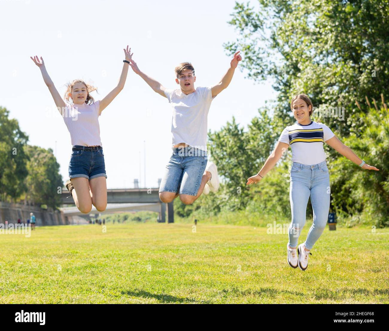 Three joyful teens jump on a lawn Stock Photo - Alamy