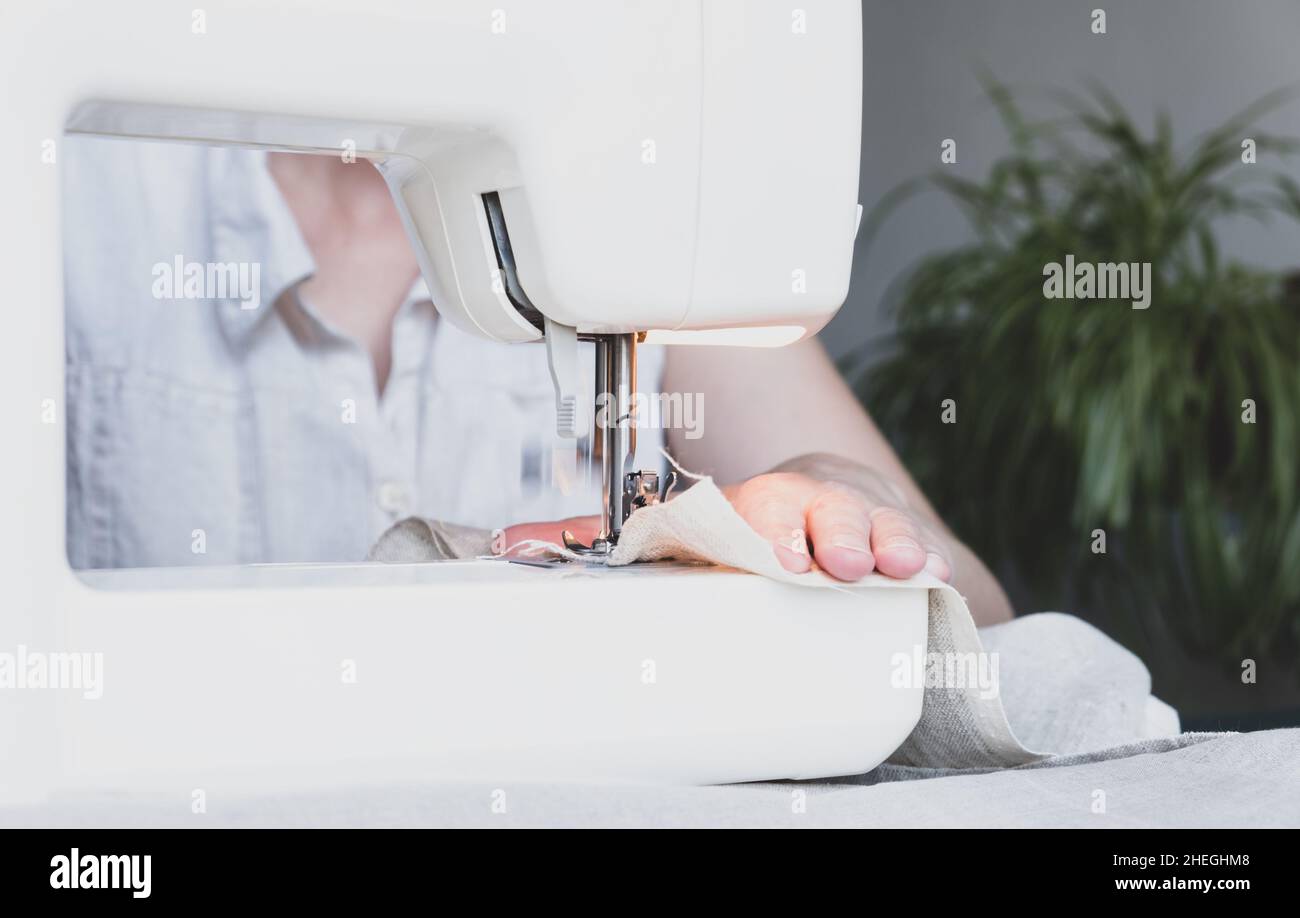 Woman sewing while sitting at her working place in home. Sewing process ...