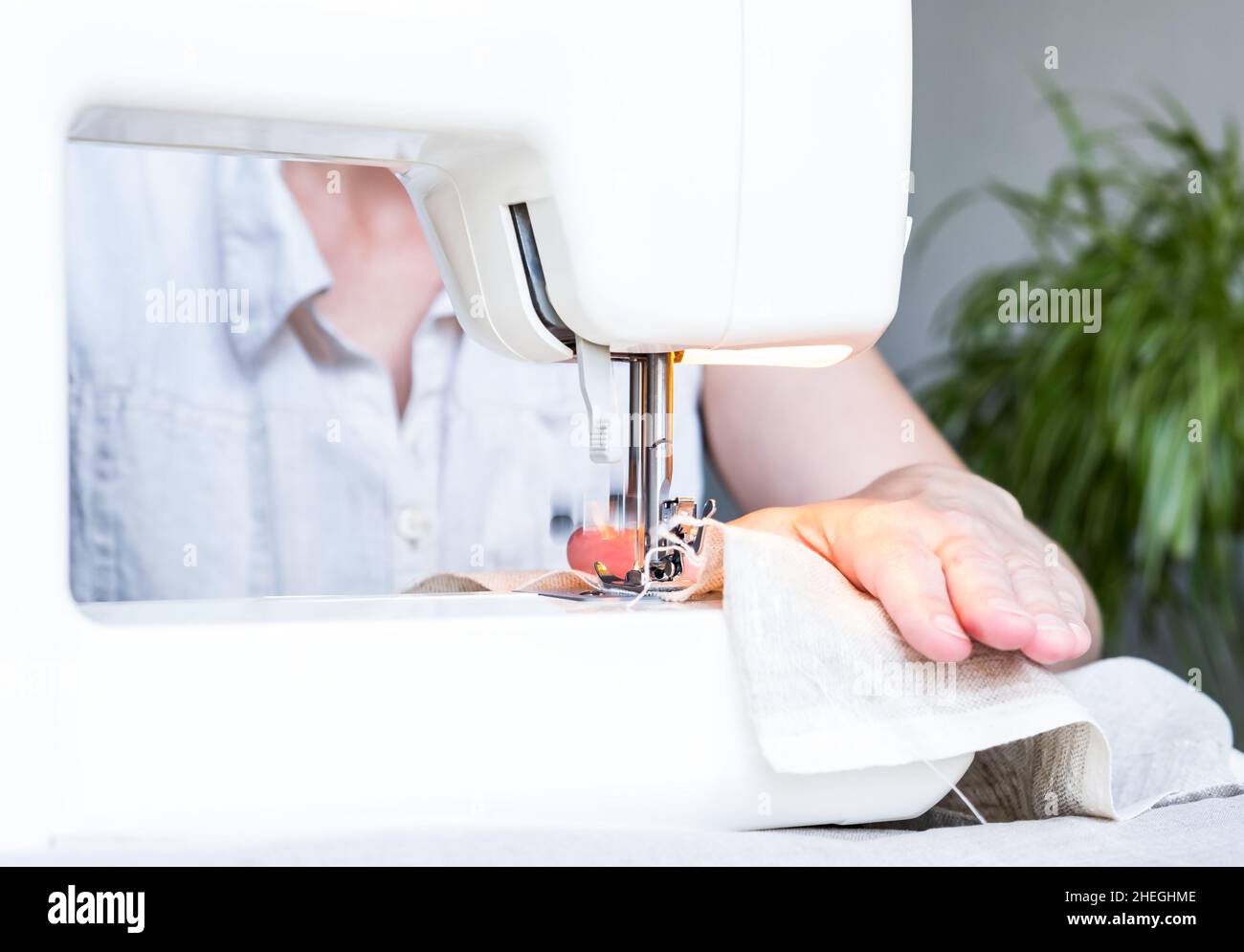 Woman sewing while sitting at her working place in home. Sewing process ...