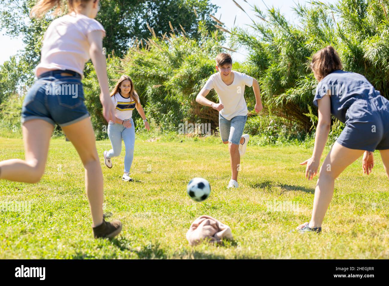 Teenagers playing football on green grass in summertime Stock Photo - Alamy