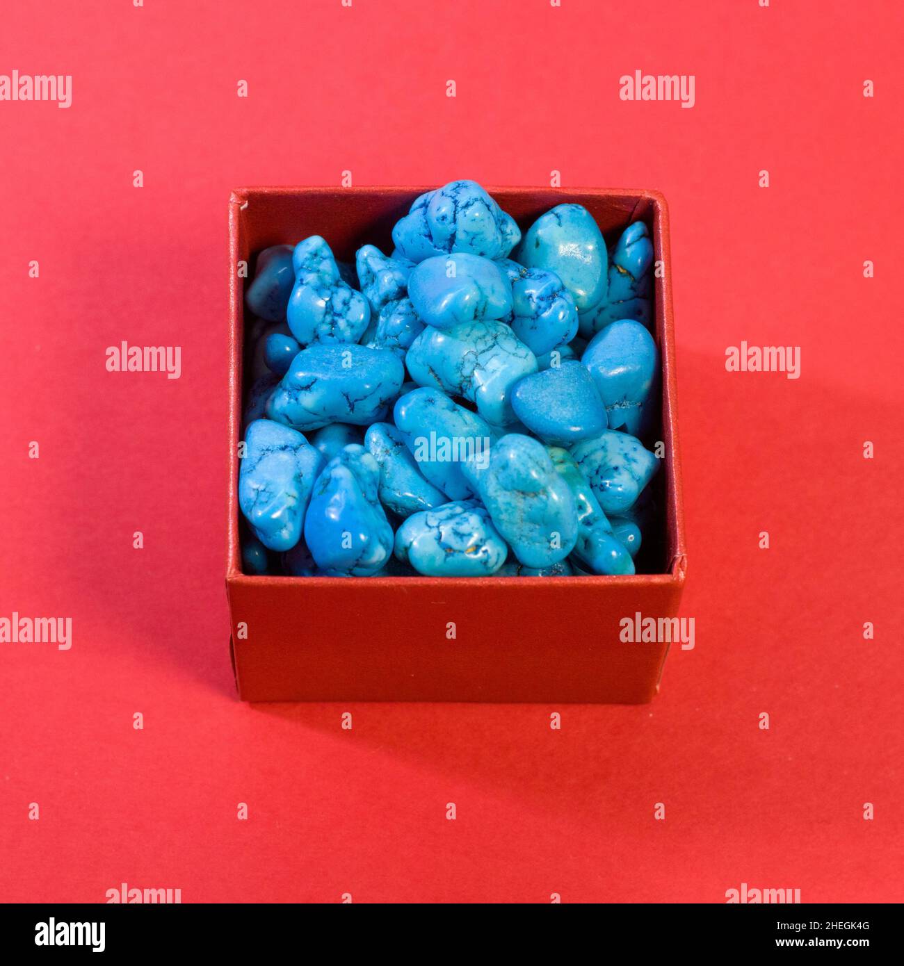 Turquoise jewel stones on bright red background, group of objects front ...