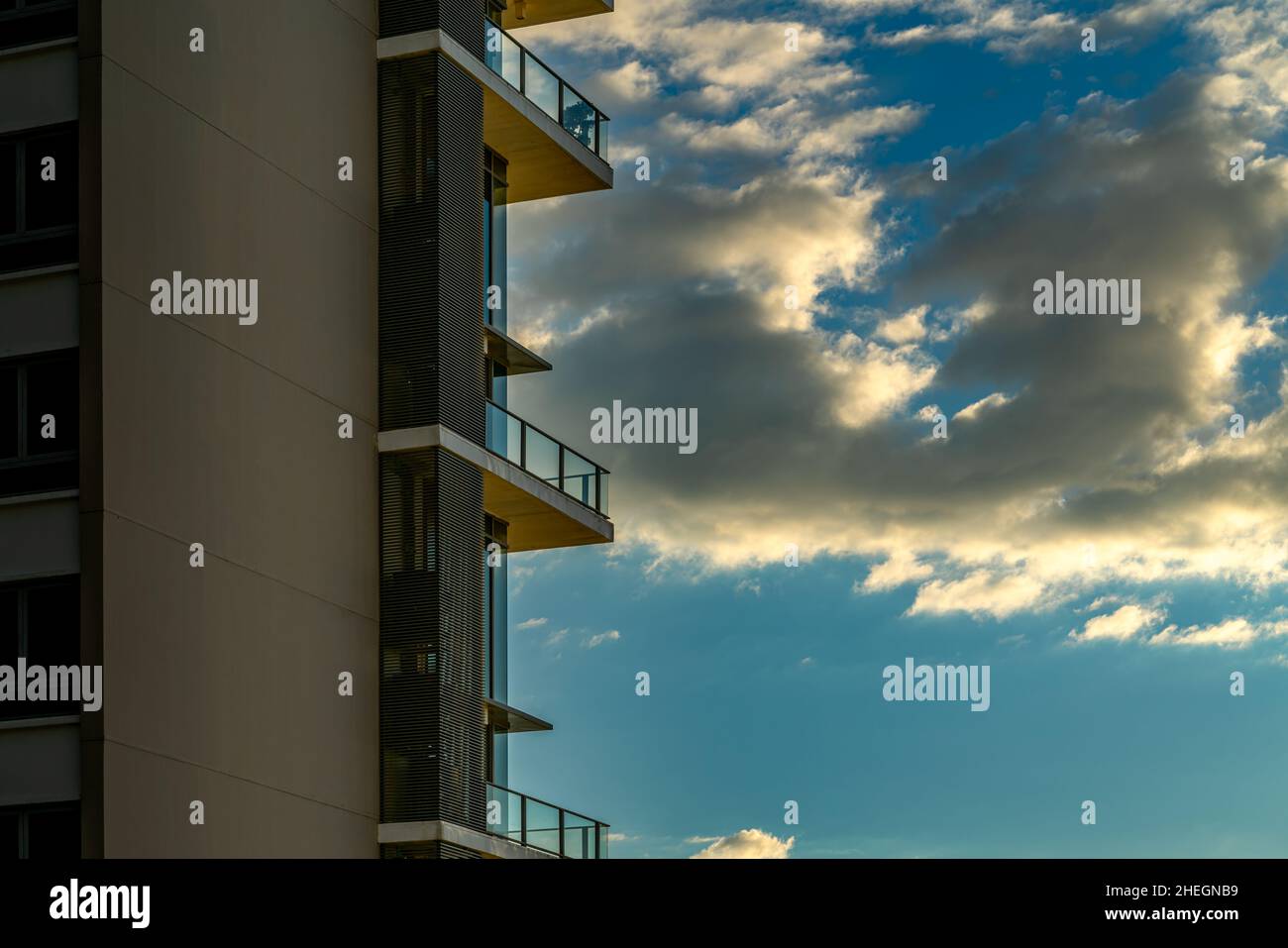 A modern high building with balconies against sunset sky and beautiful ...