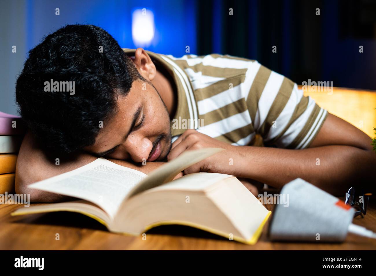Young student sleeping on table due to taired of reading for ...