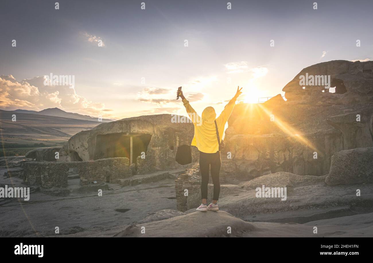 Woman stands on rock in historical place with spreaded hands out of joy ...
