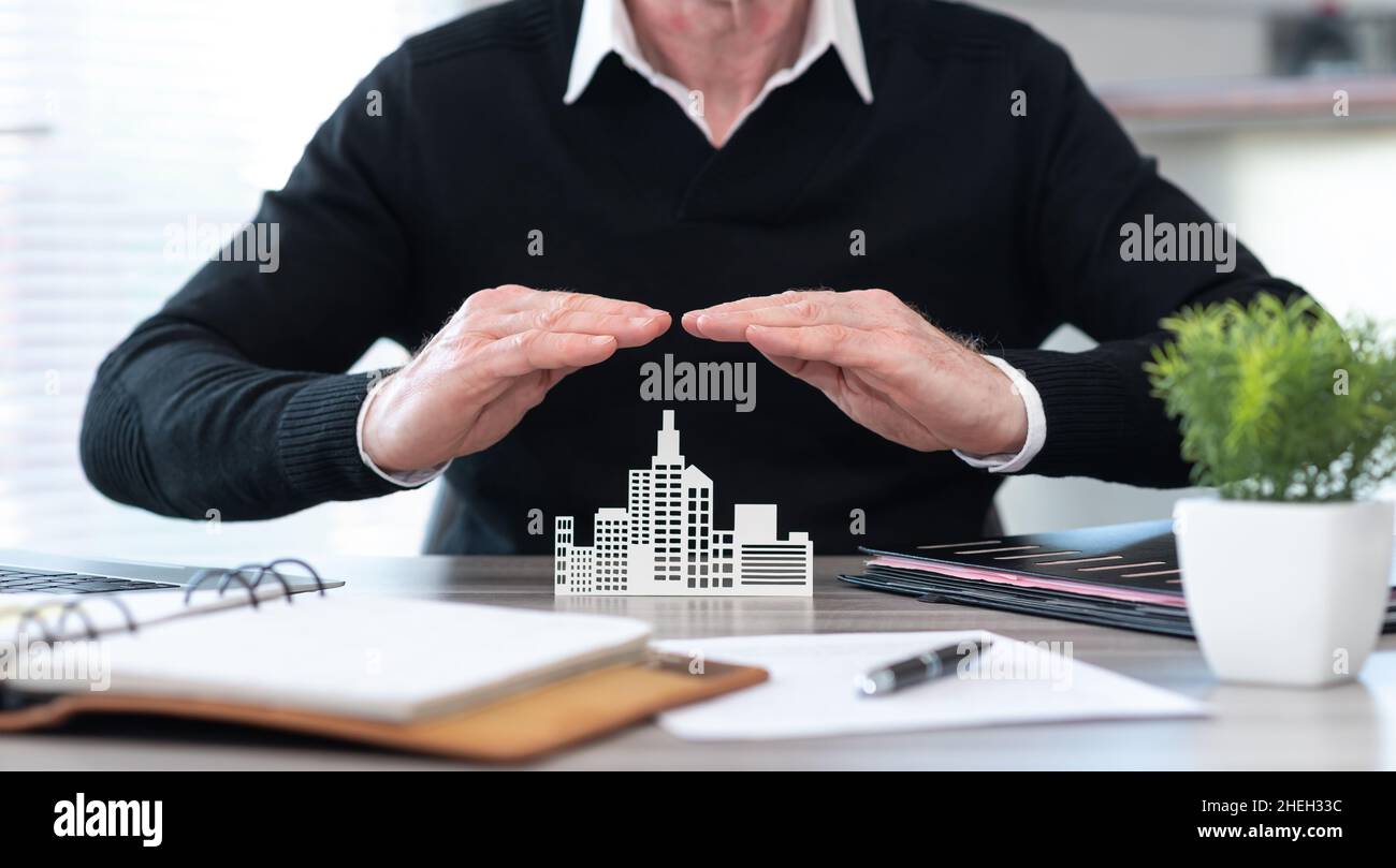 Insurer protecting an office building with his hands Stock Photo - Alamy