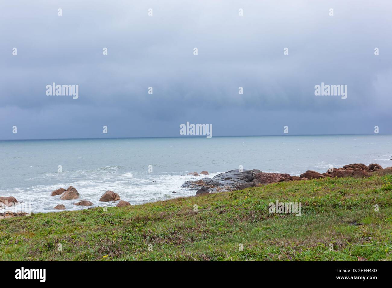 Beach coastline rocks with distant rain storm coming over the ocean ...