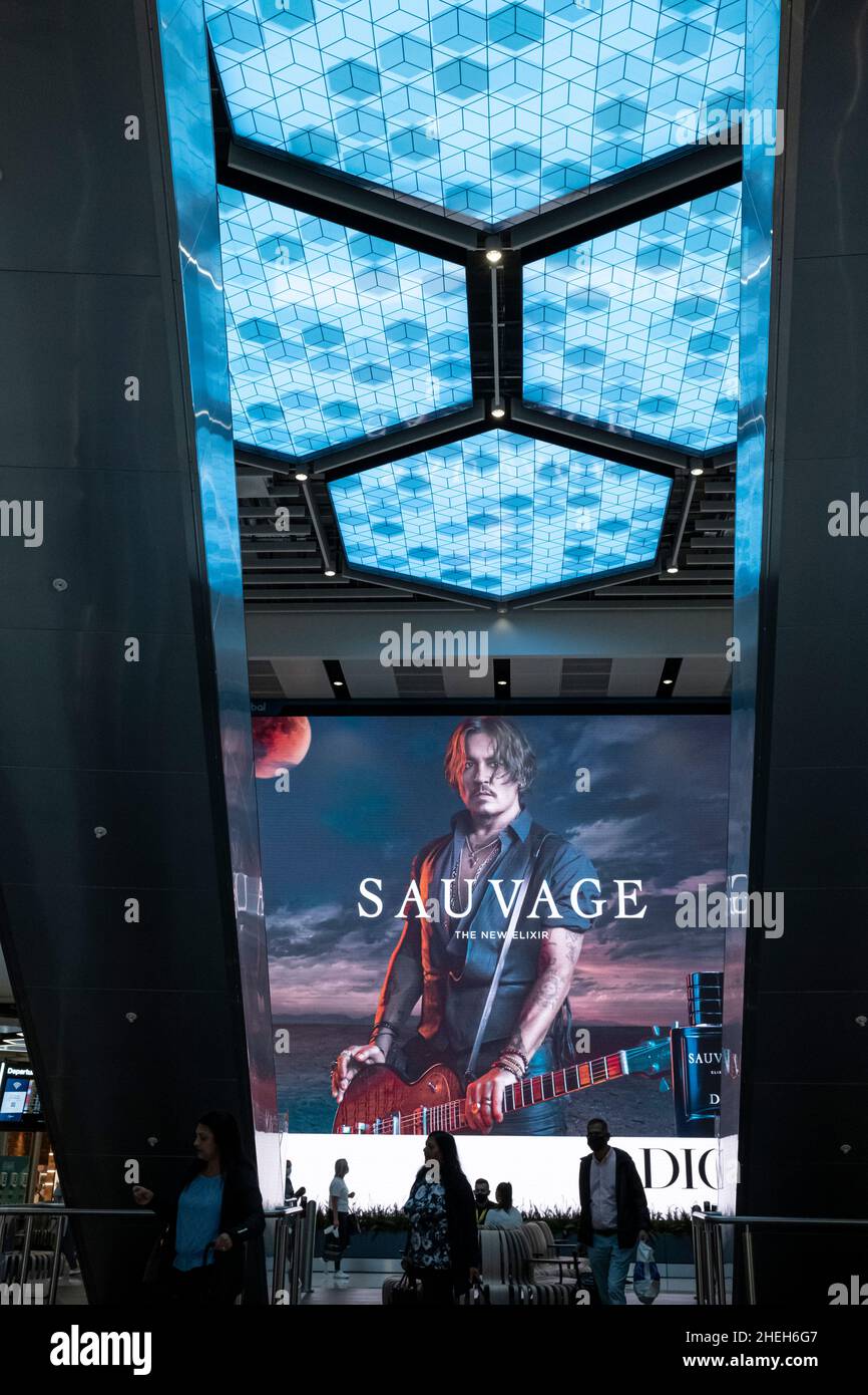 Passengers passing in front of a large digital advertising screen in ...