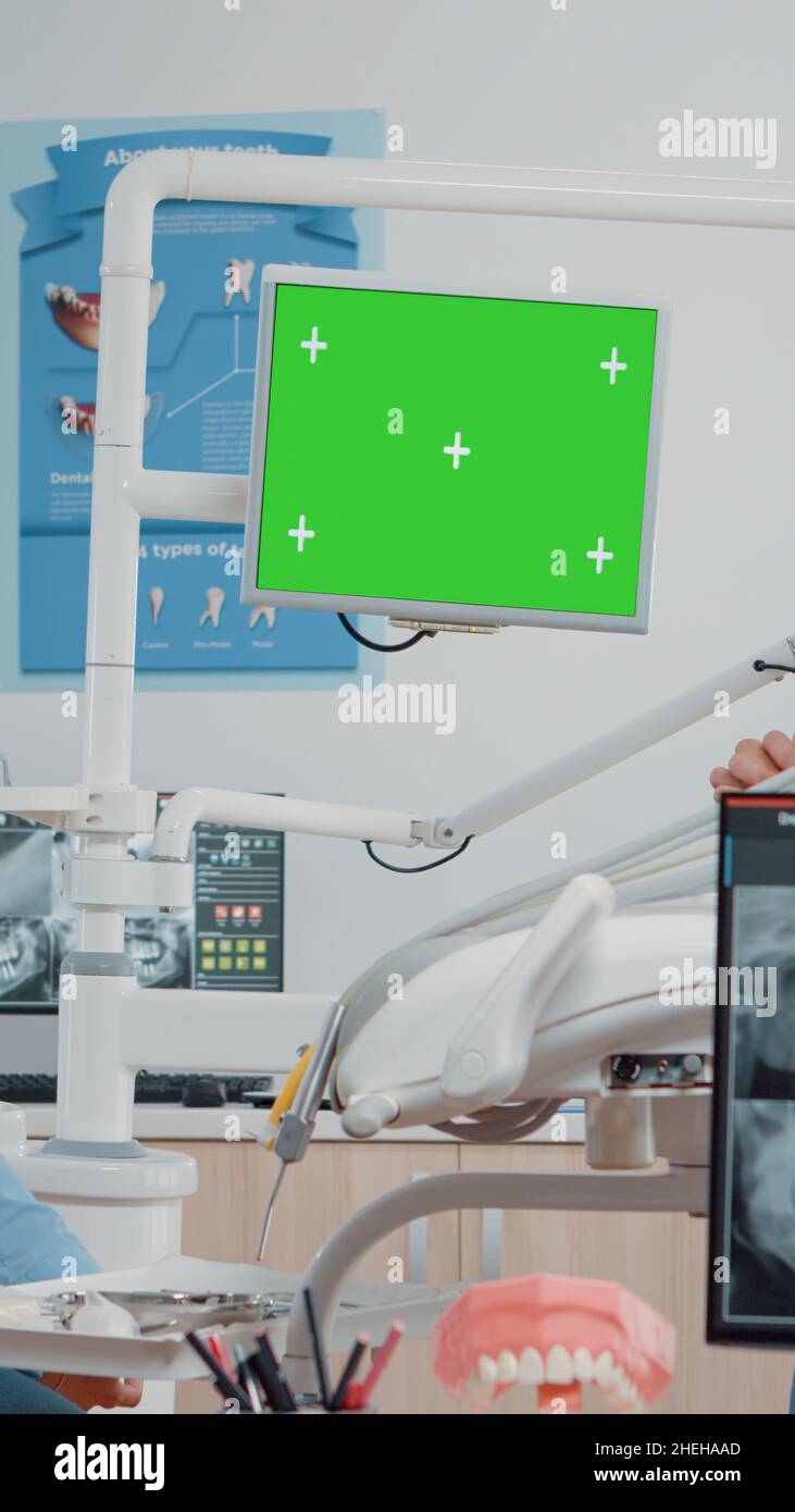 Dentist and assistant looking at green screen on monitor in dental ...