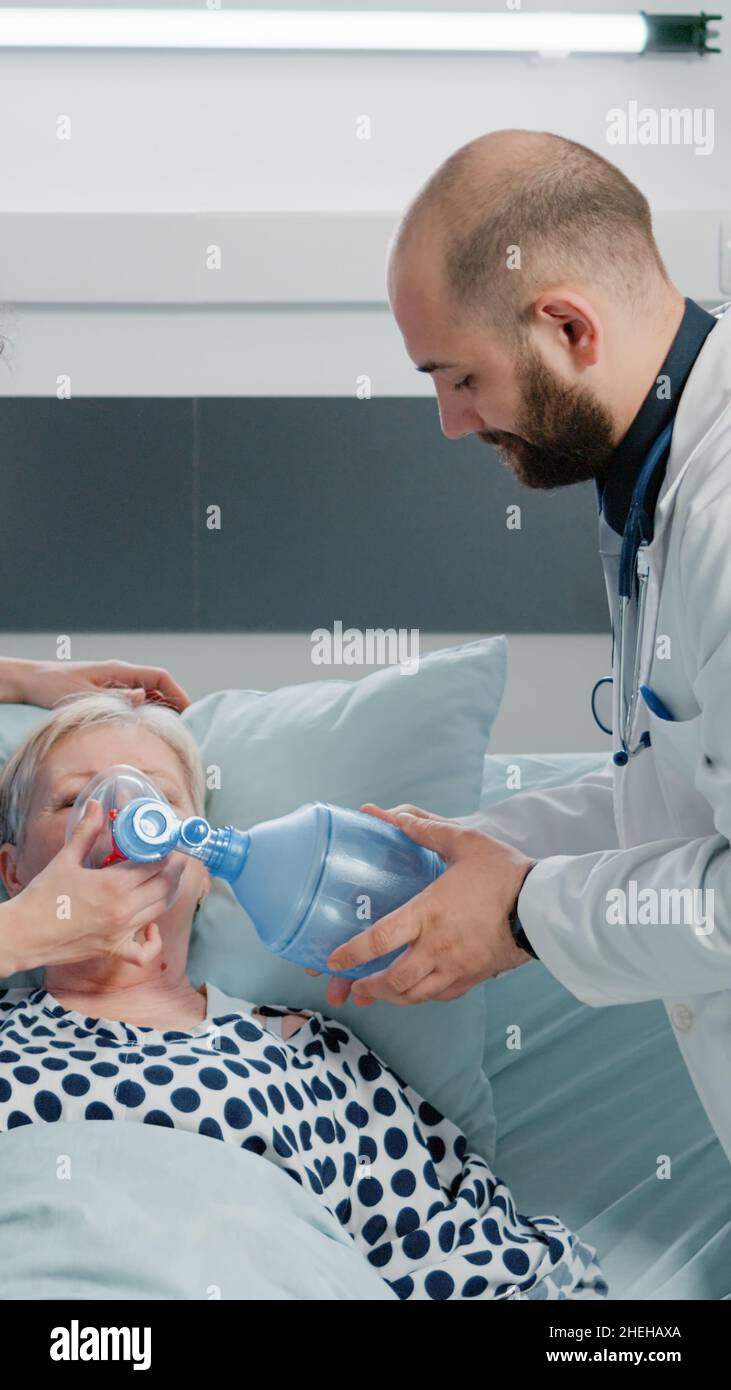Doctor and nurse using oxygen tube and oximeter on ill patient ...