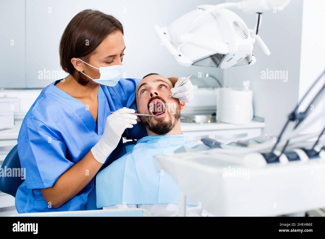 Stomatologist girl in uniform is taking visional inspection of a man ...