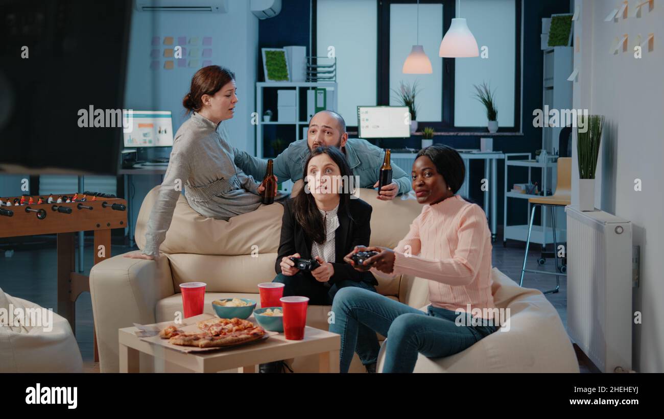 Colleagues playing video games on console with controller after work ...