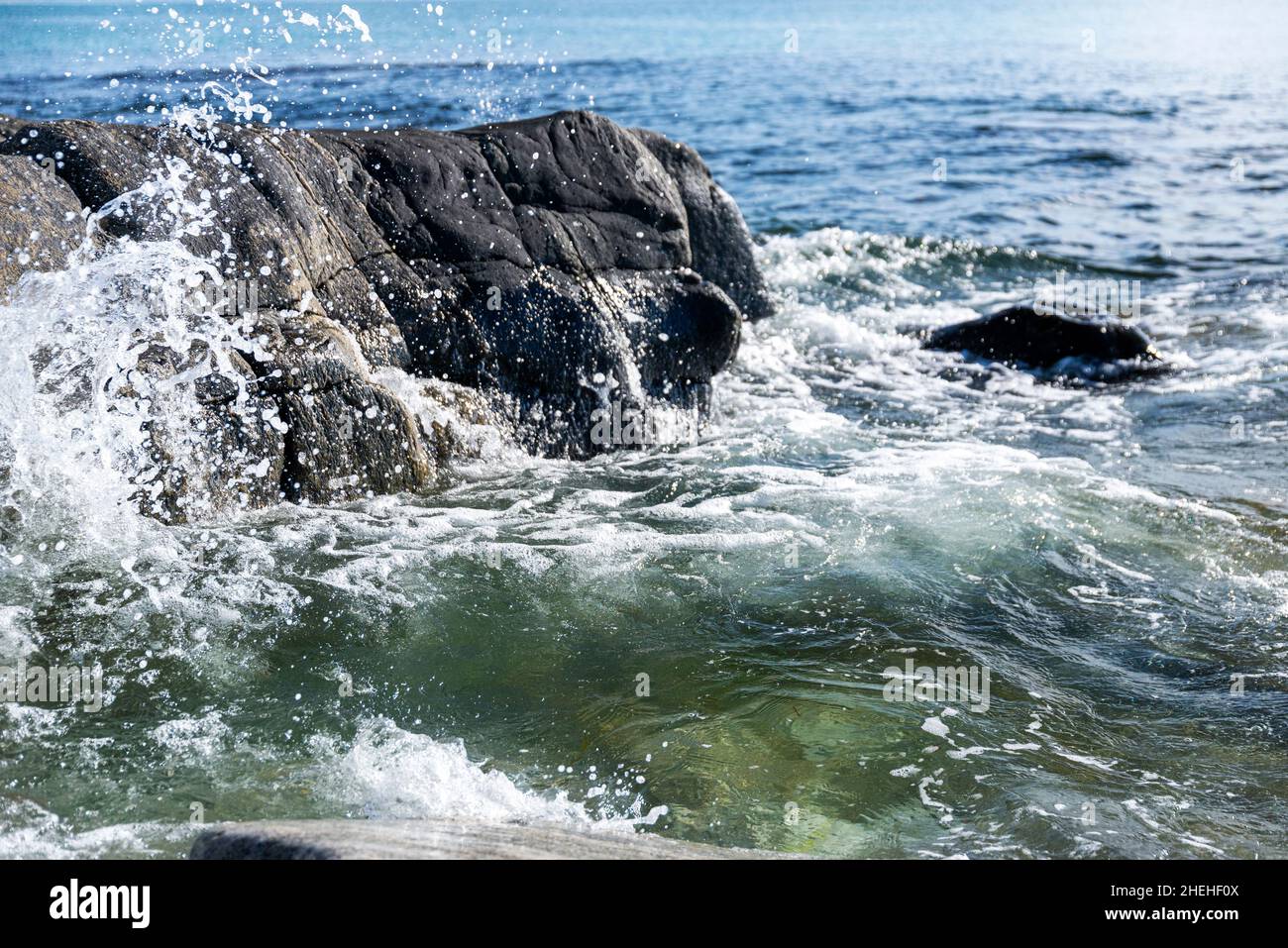 Splashing waves captured crashing against a large rock Stock Photo - Alamy