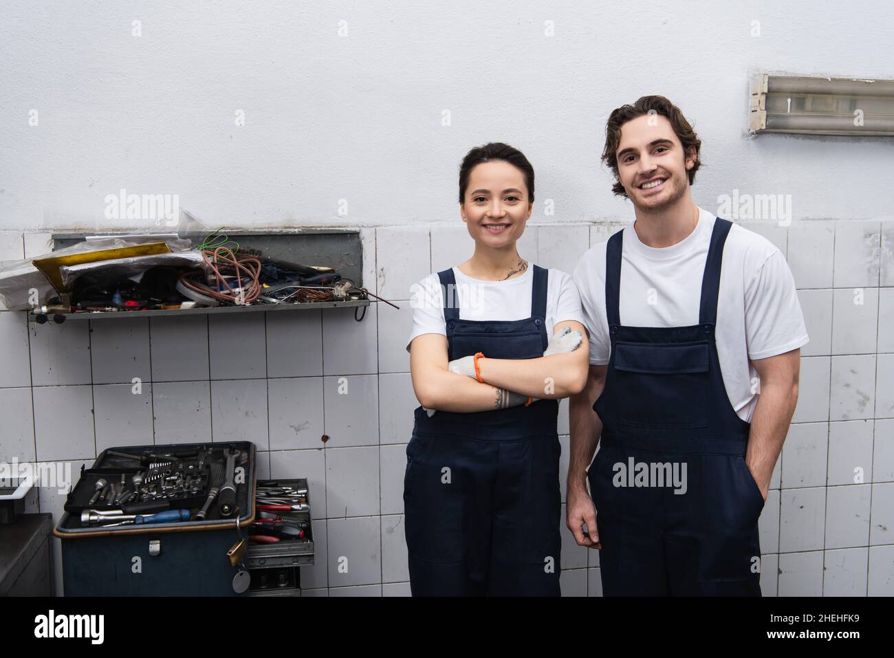 Smiling mechanics looking at camera near tools in car service Stock ...