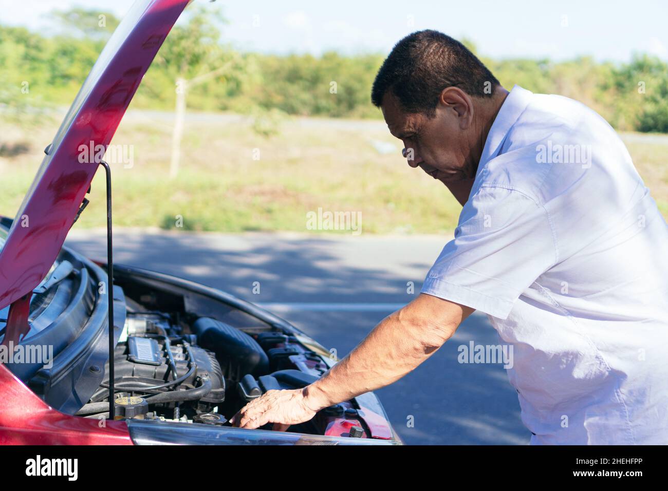man calling for road assistance, standing next to a broken down car ...