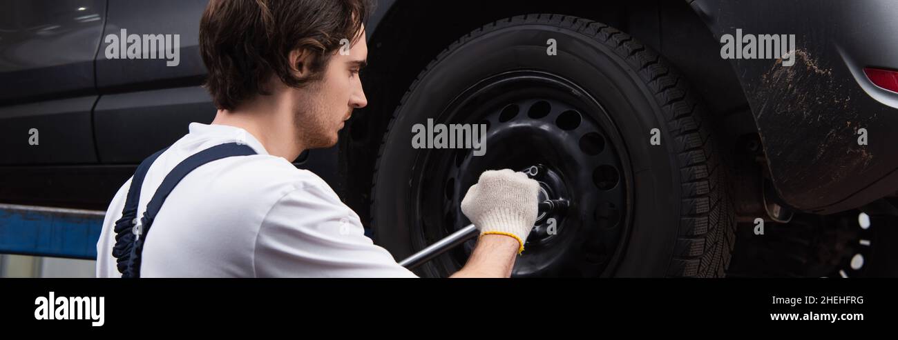Side view of mechanic unscrewing car wheel in service, banner Stock ...