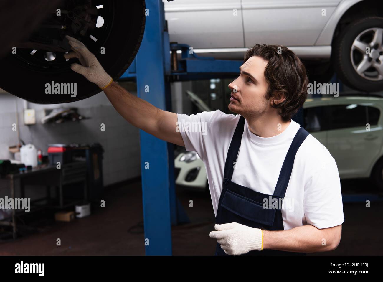 Side view of workman checking car wheel in garage Stock Photo - Alamy
