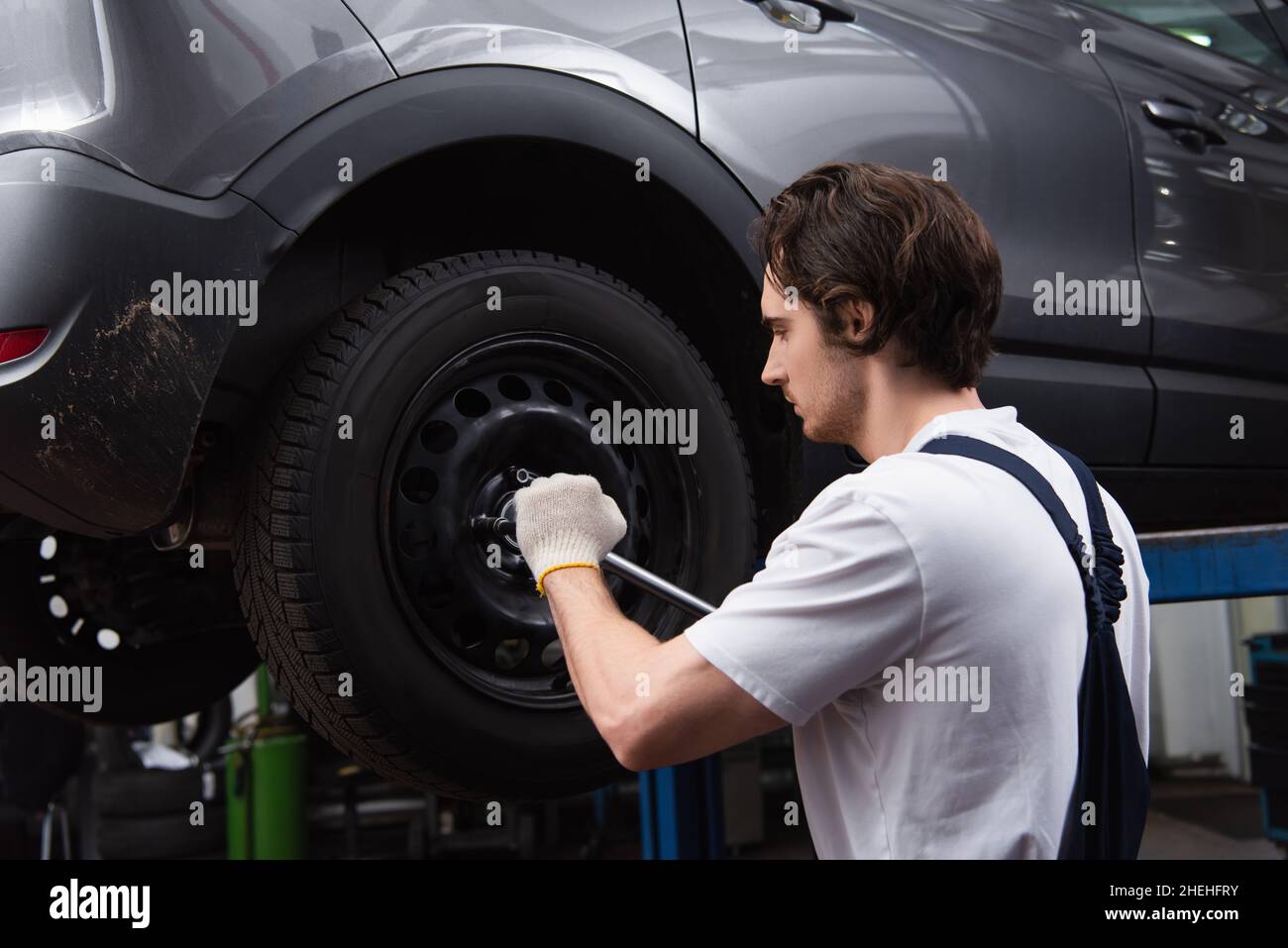 Side view of workman unscrewing car wheel in garage Stock Photo - Alamy