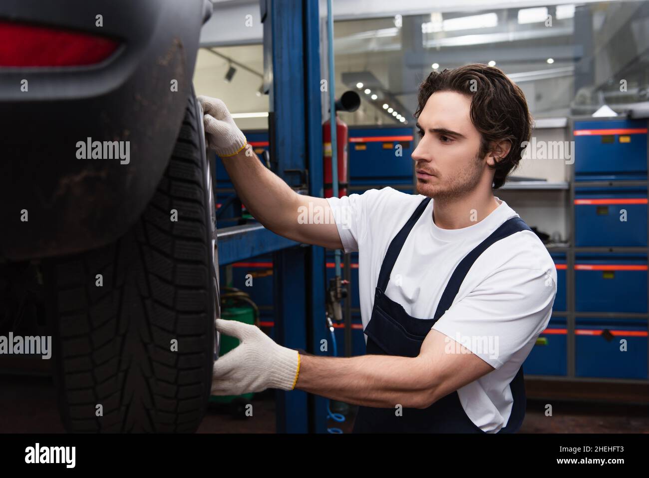 Young mechanic working with wheel disk and car in garage Stock Photo ...