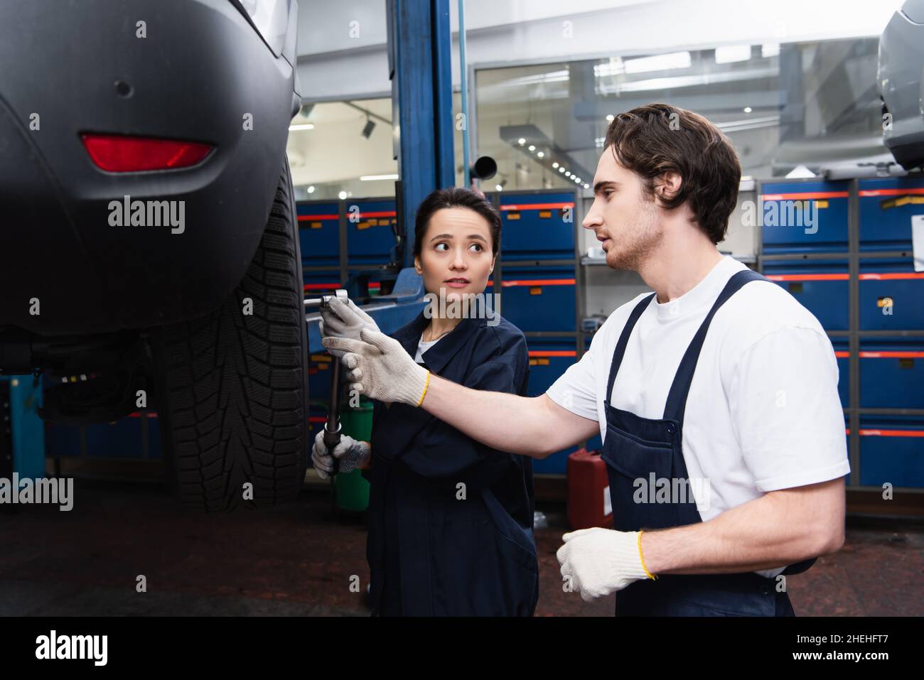 Young mechanics working with car wheel in service Stock Photo - Alamy