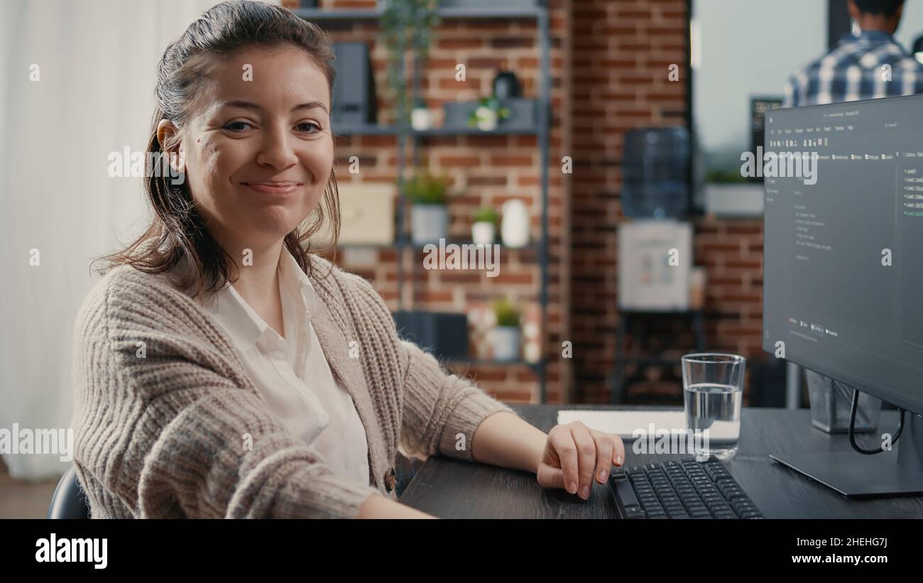 Software Engineer Typing Source Code On Computer Keyboard Turning Head And Smiling At Camera
