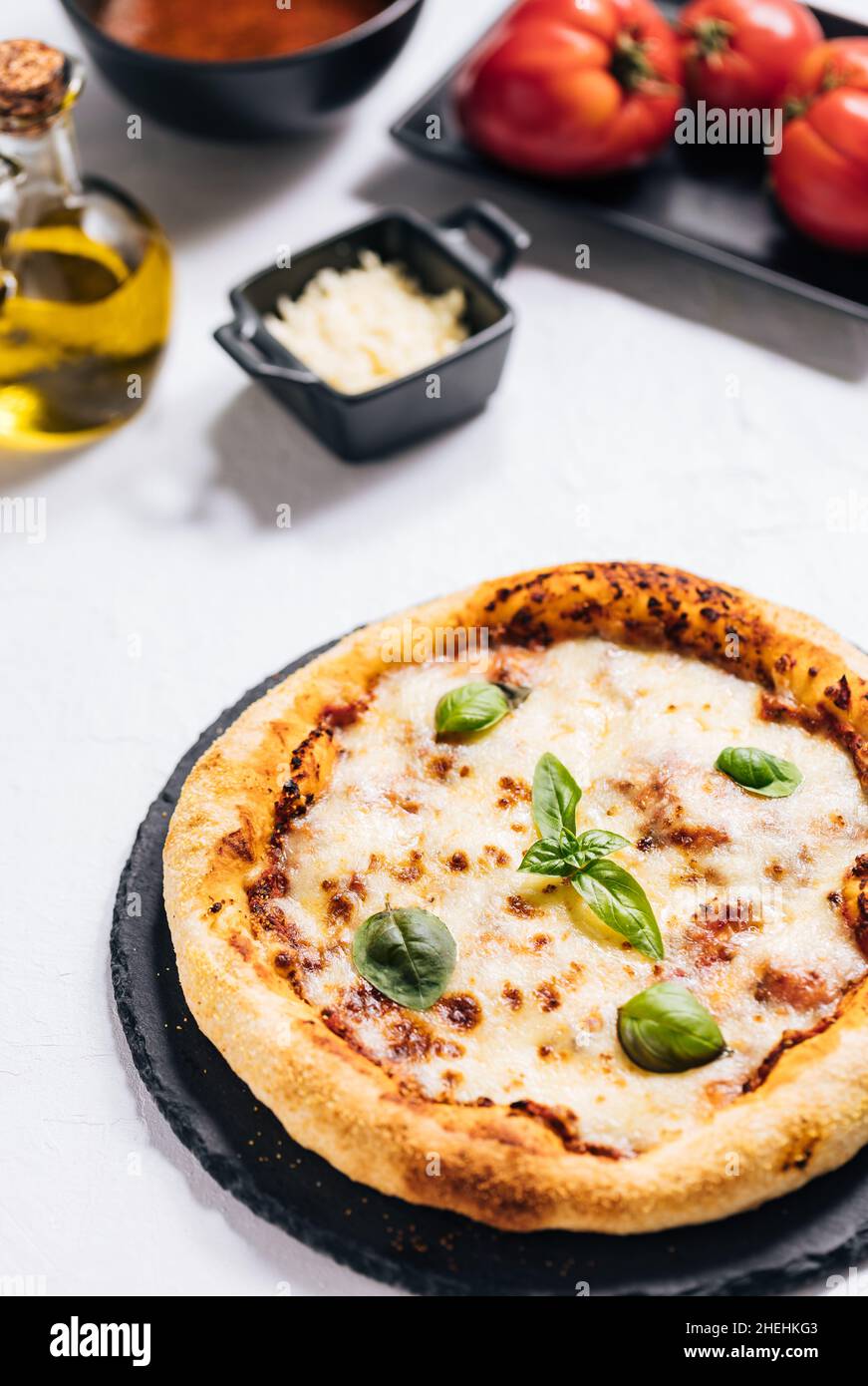 Traditional italian pizza on a white rustic background with basil ...