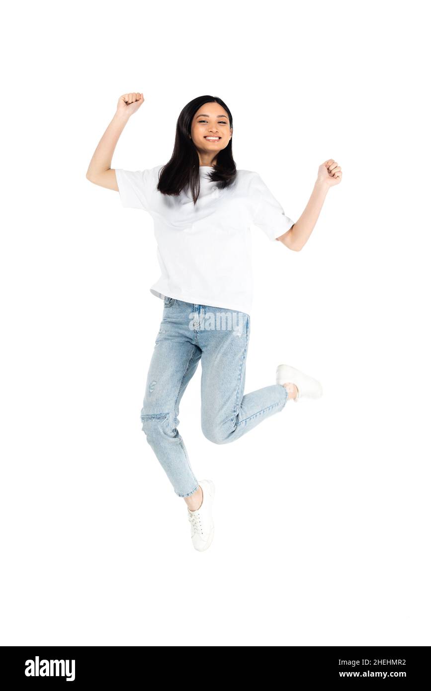 full length view of cheerful asian woman in t-shirt and jeans ...