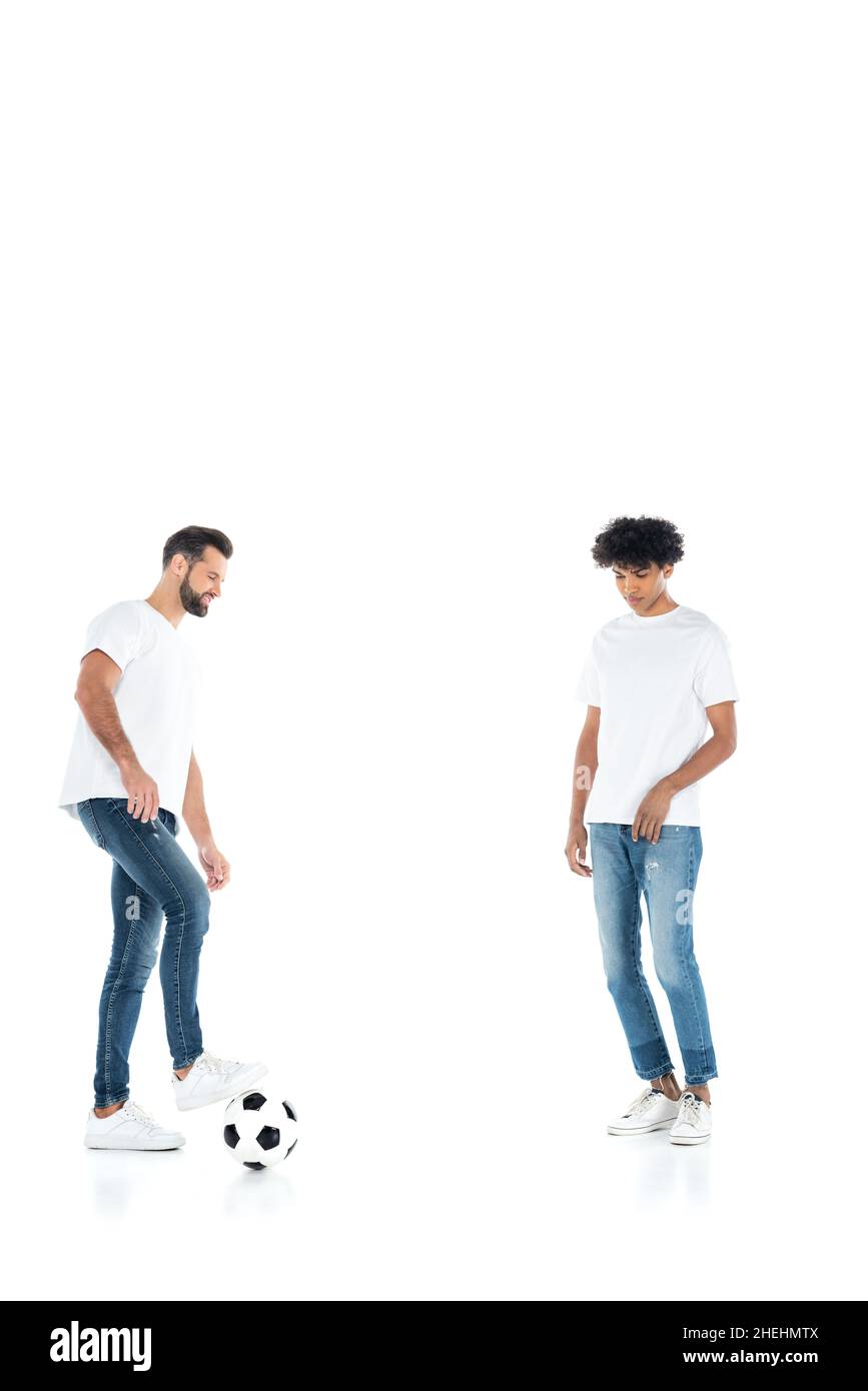 full length view of smiling man playing football with african american ...