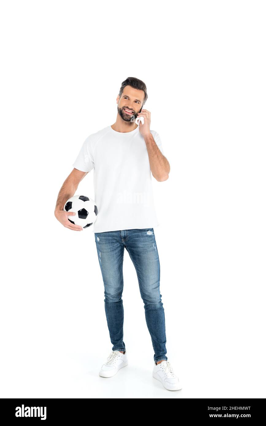 full length view of man with soccer ball talking on cellphone on white ...