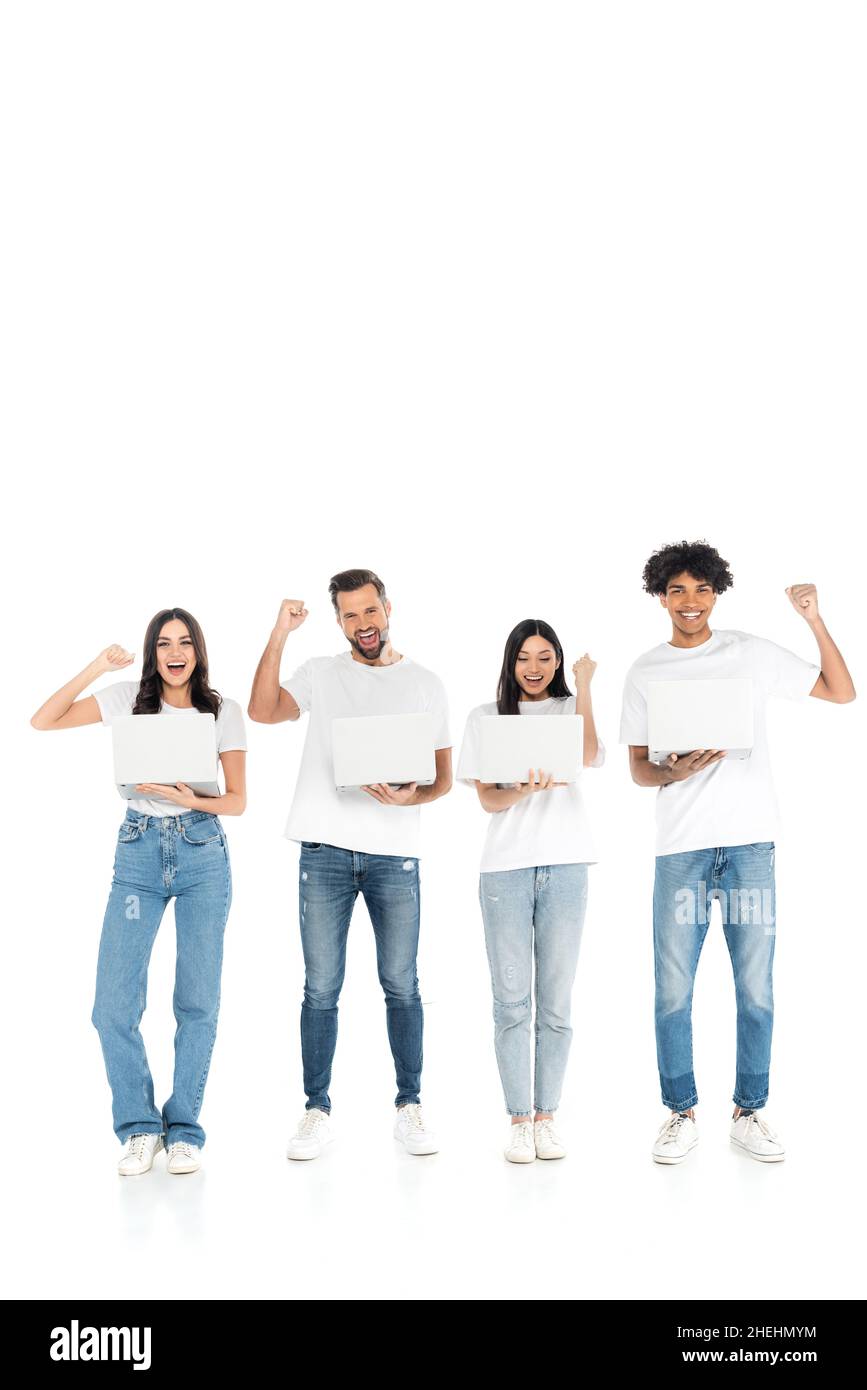 full length view of happy multiethnic friends with laptops showing ...