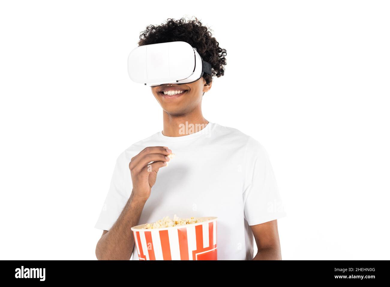 smiling african american man eating popcorn while gaming in vr headset ...