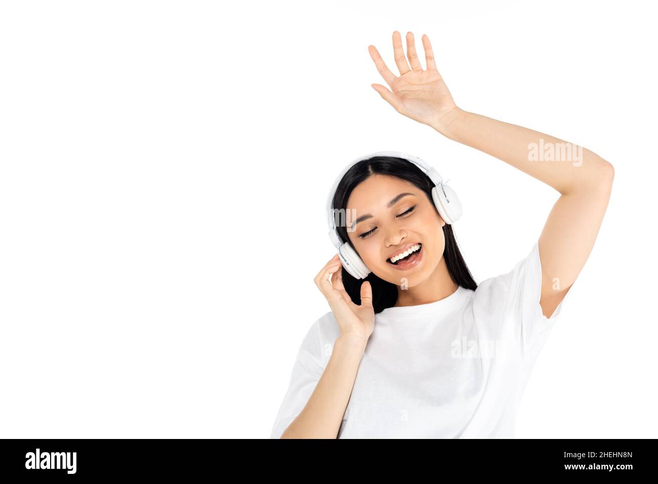 joyful asian woman in headphones dancing with closed eyes isolated on ...